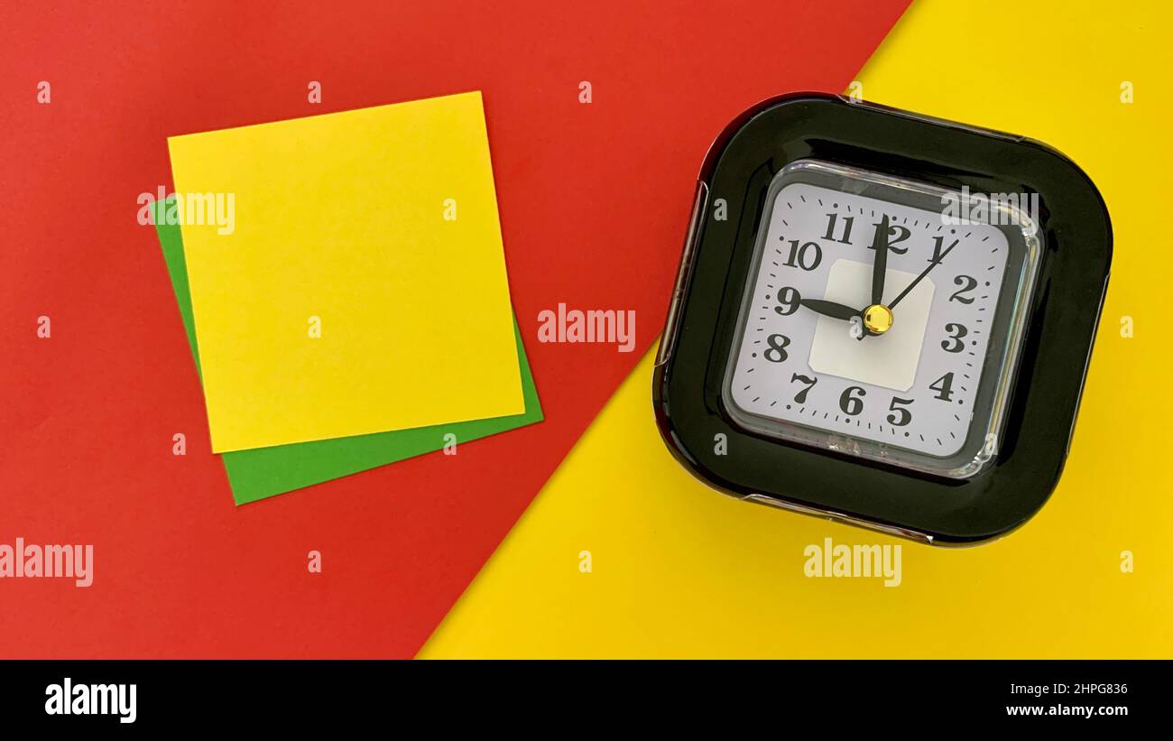 Top view of sticky note and alarm clock with red and yellow color ...