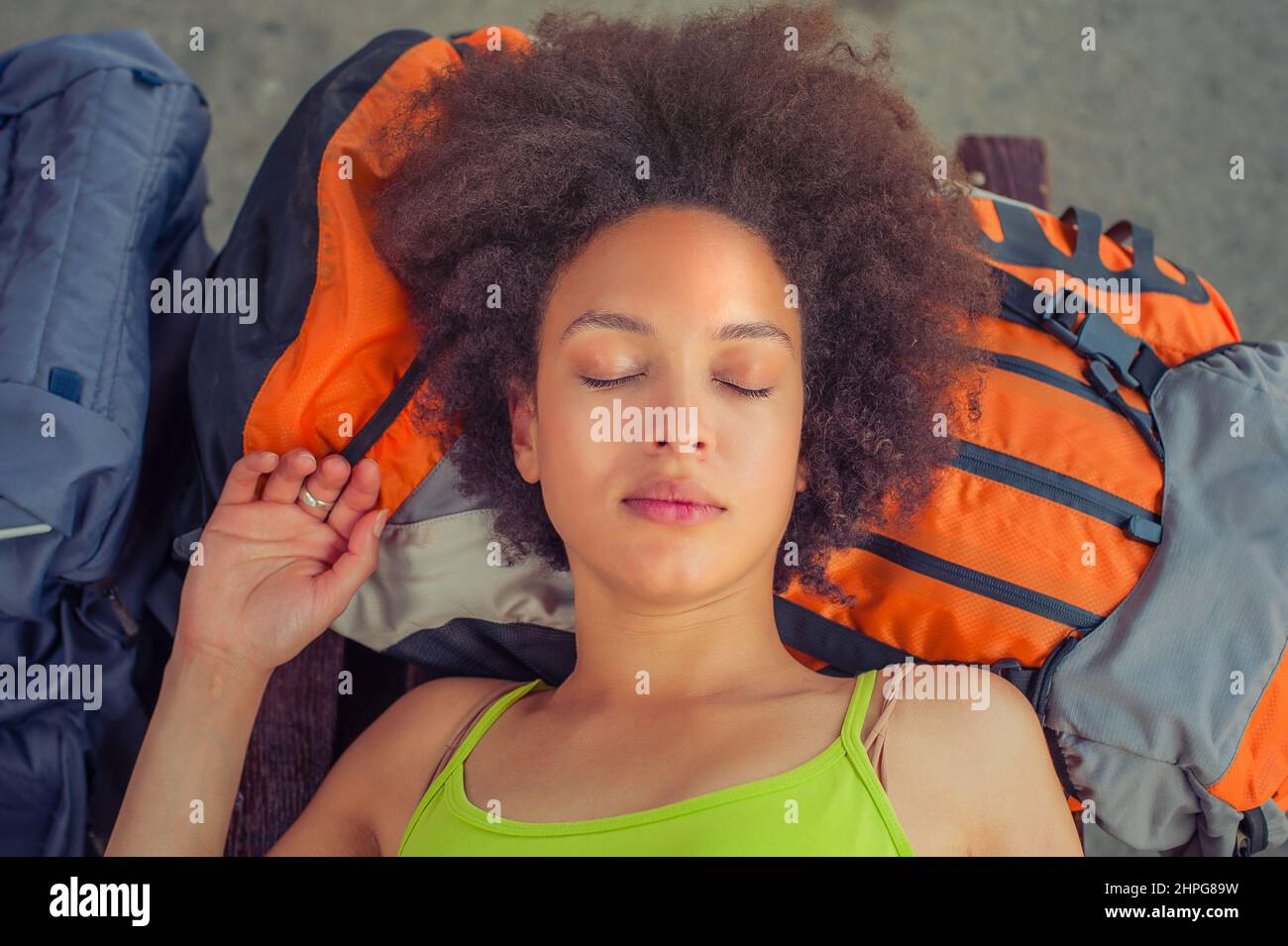 Closeup of beautiful female backpacker tourist napping on a bench and ...