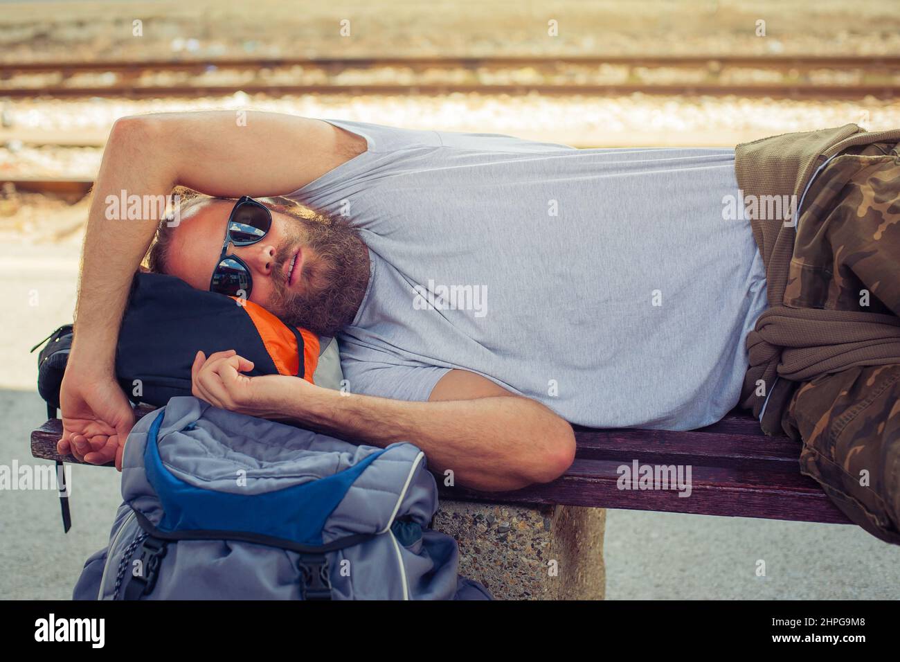 Handsome male backpacker tourist napping on a bench and baggage at the ...
