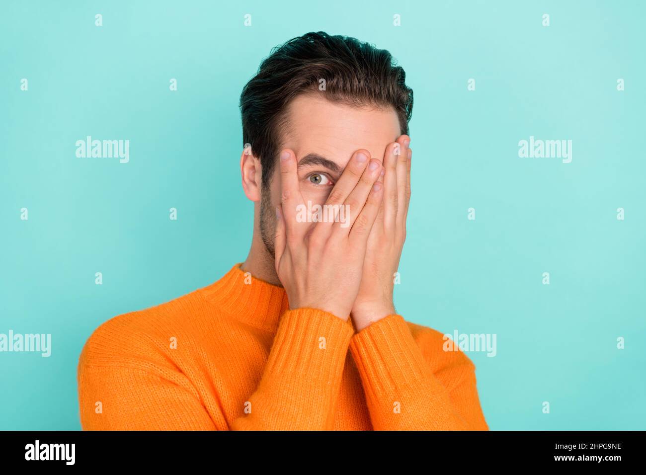 Portrait of puzzled young person arms covering face one eye peeking ...