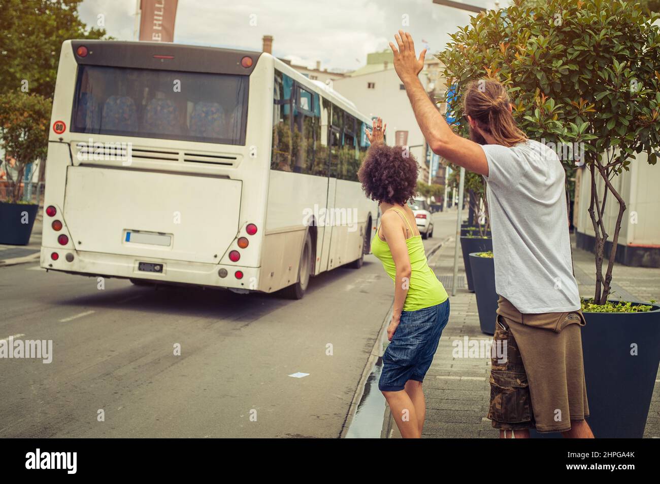 Young couple waving goodbye to their friends on the bus at bus station ...