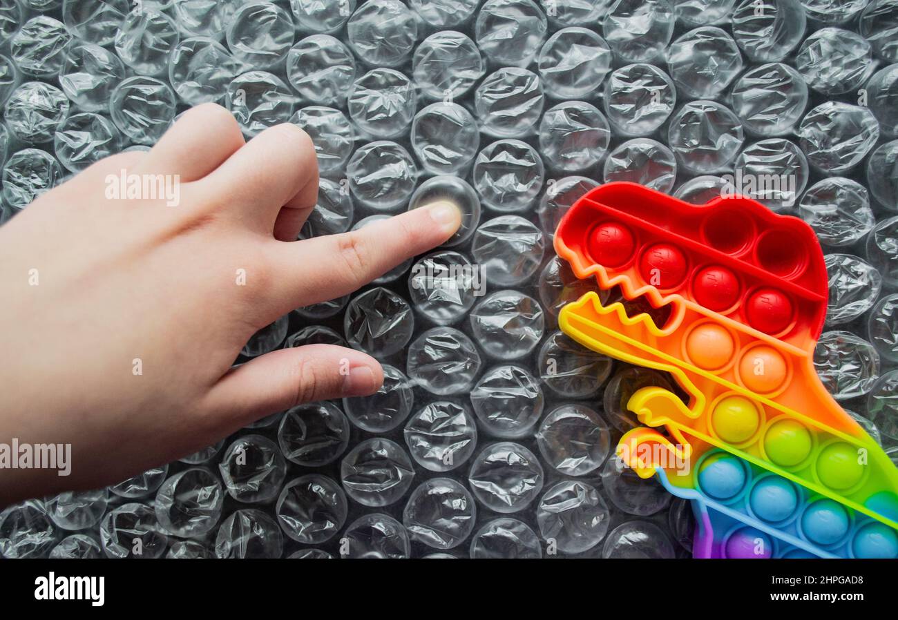 Toy pop it dinosaur rainbow colors on a bubble wrap background with ...