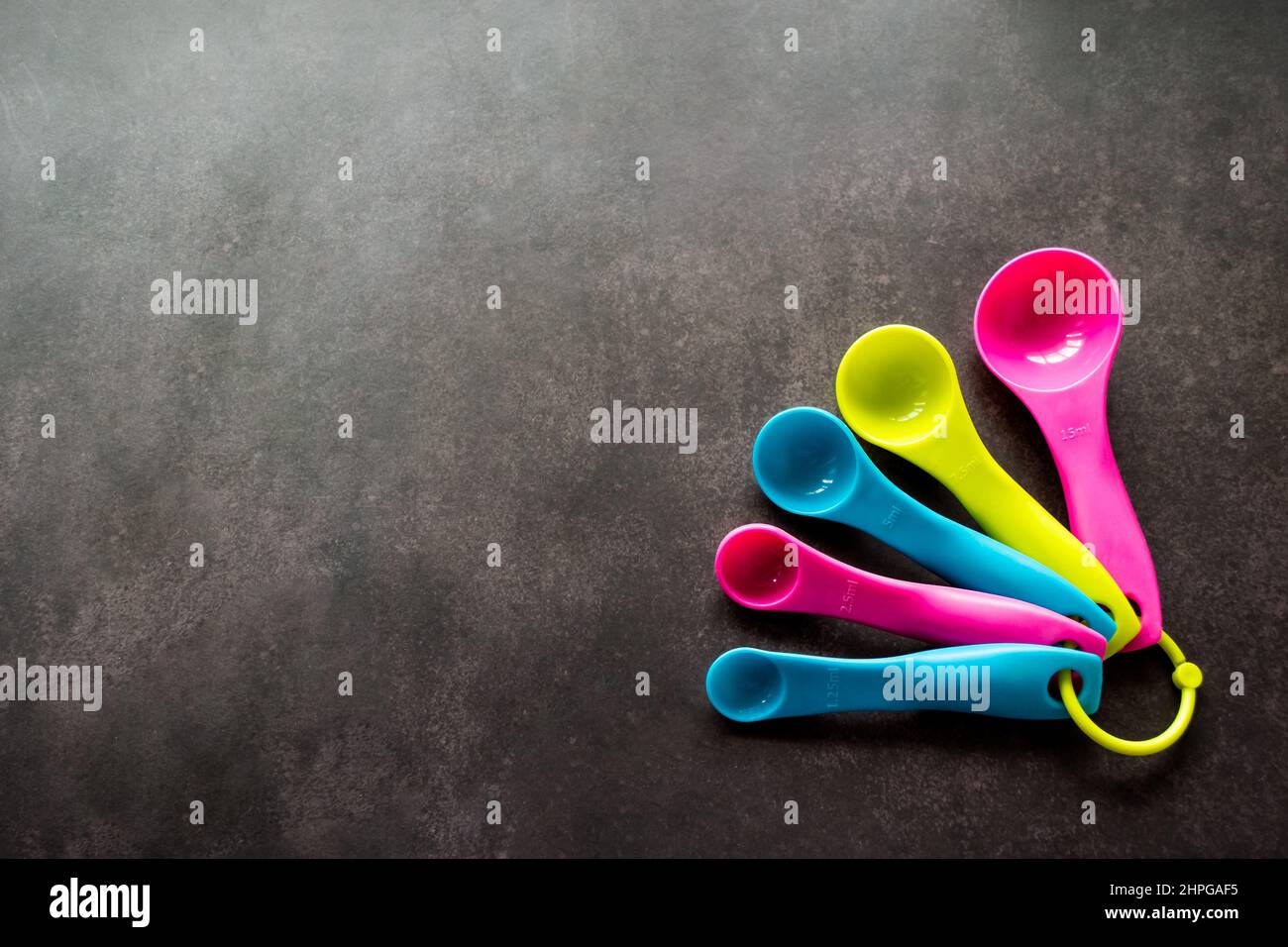 Multicolored measuring spoons of pink, blue and yellow-green colors and ...