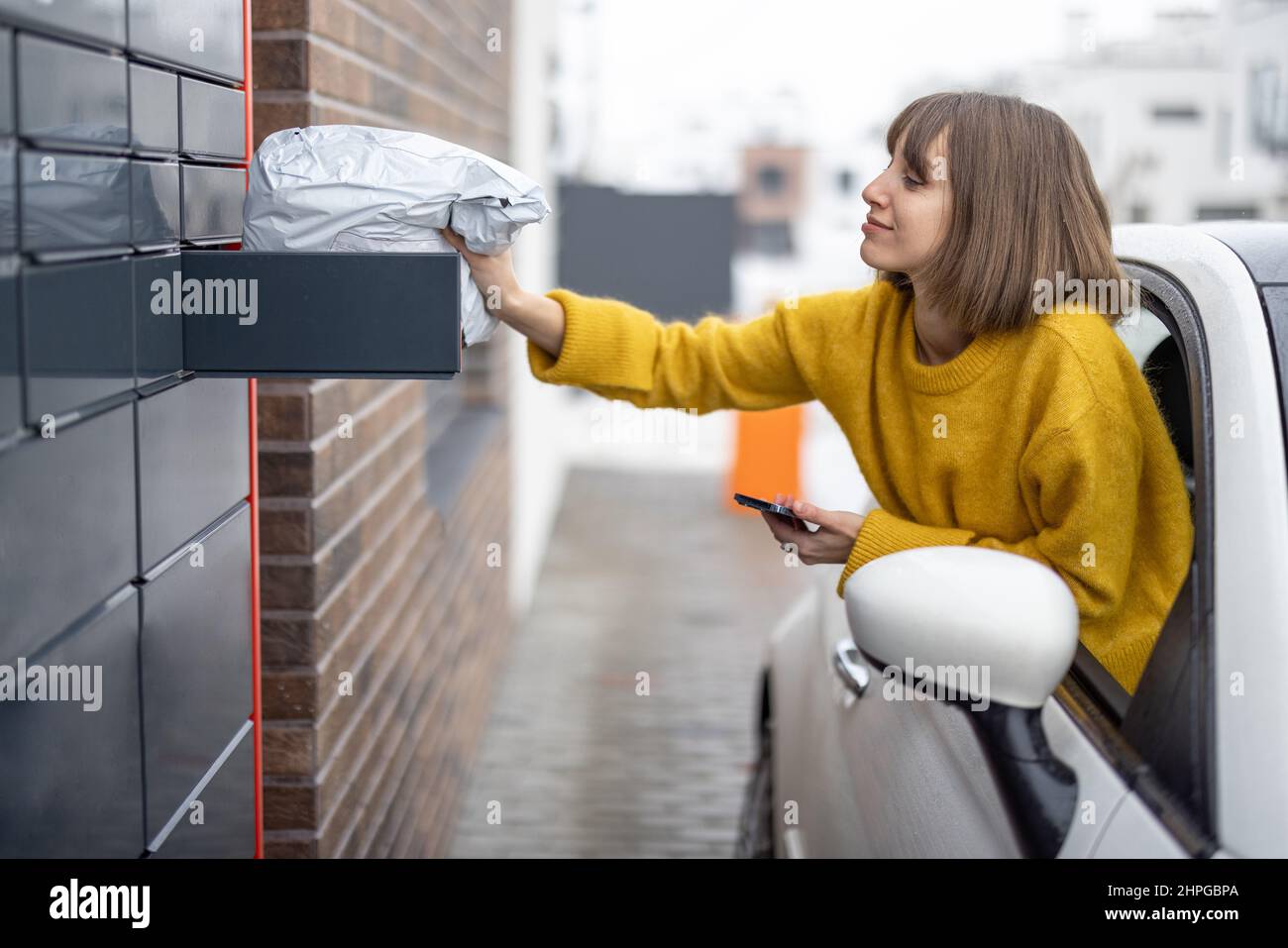 Woman getting parcel from the post office terminal right out of the car ...