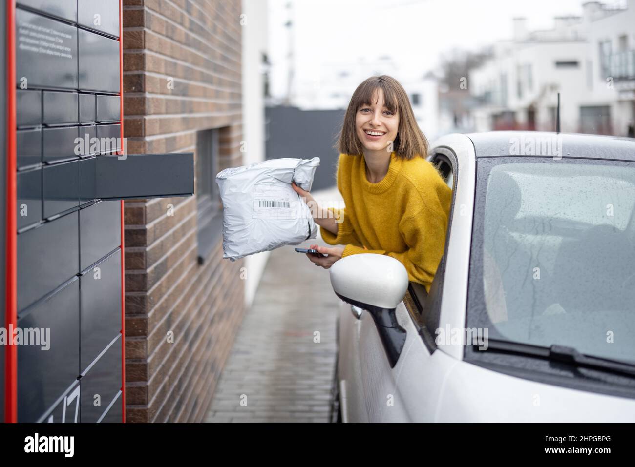 Woman getting parcel from the post office terminal right out of the car ...