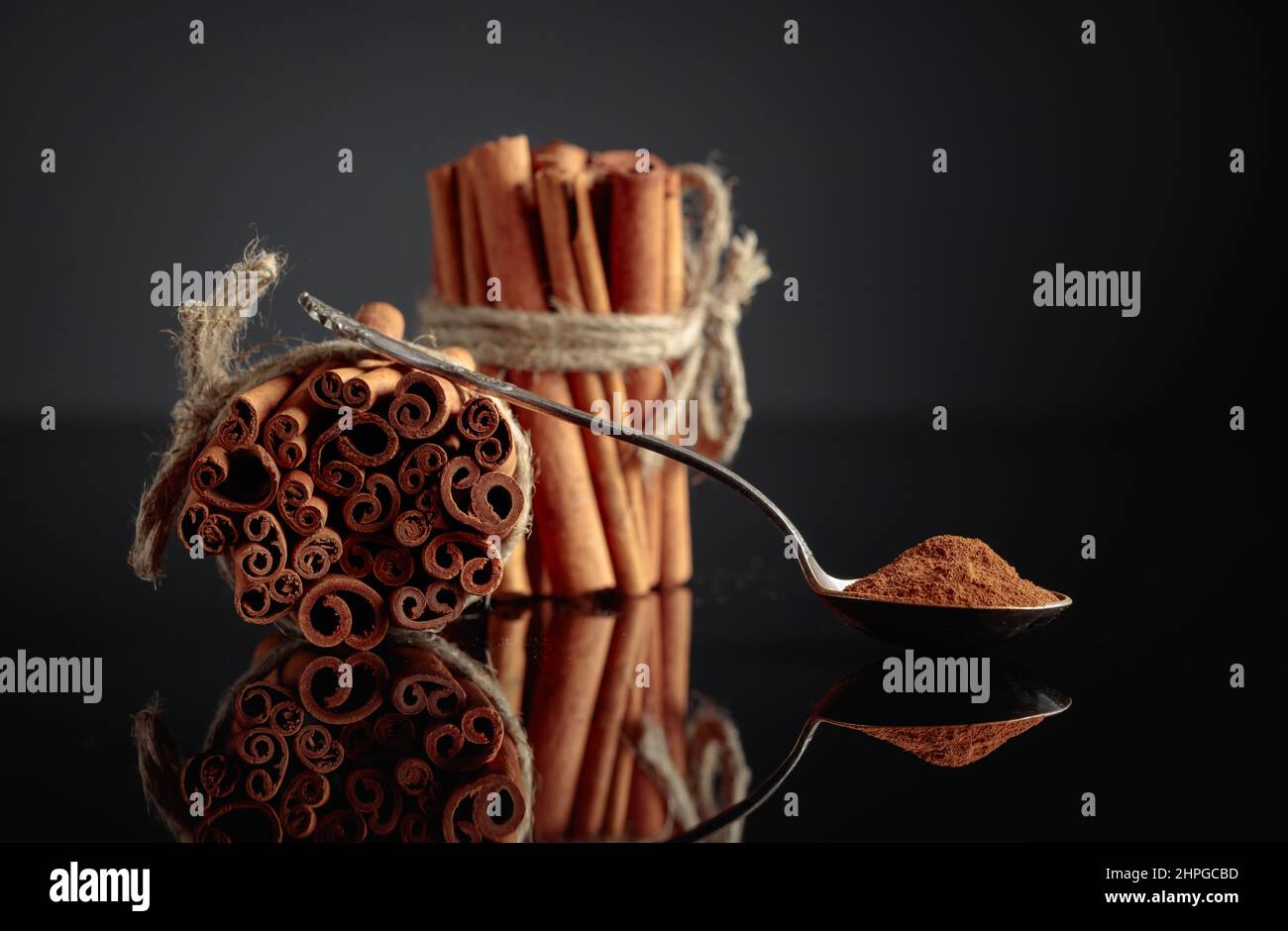 Ground cinnamon, cinnamon sticks, tied with jute rope on a black ...