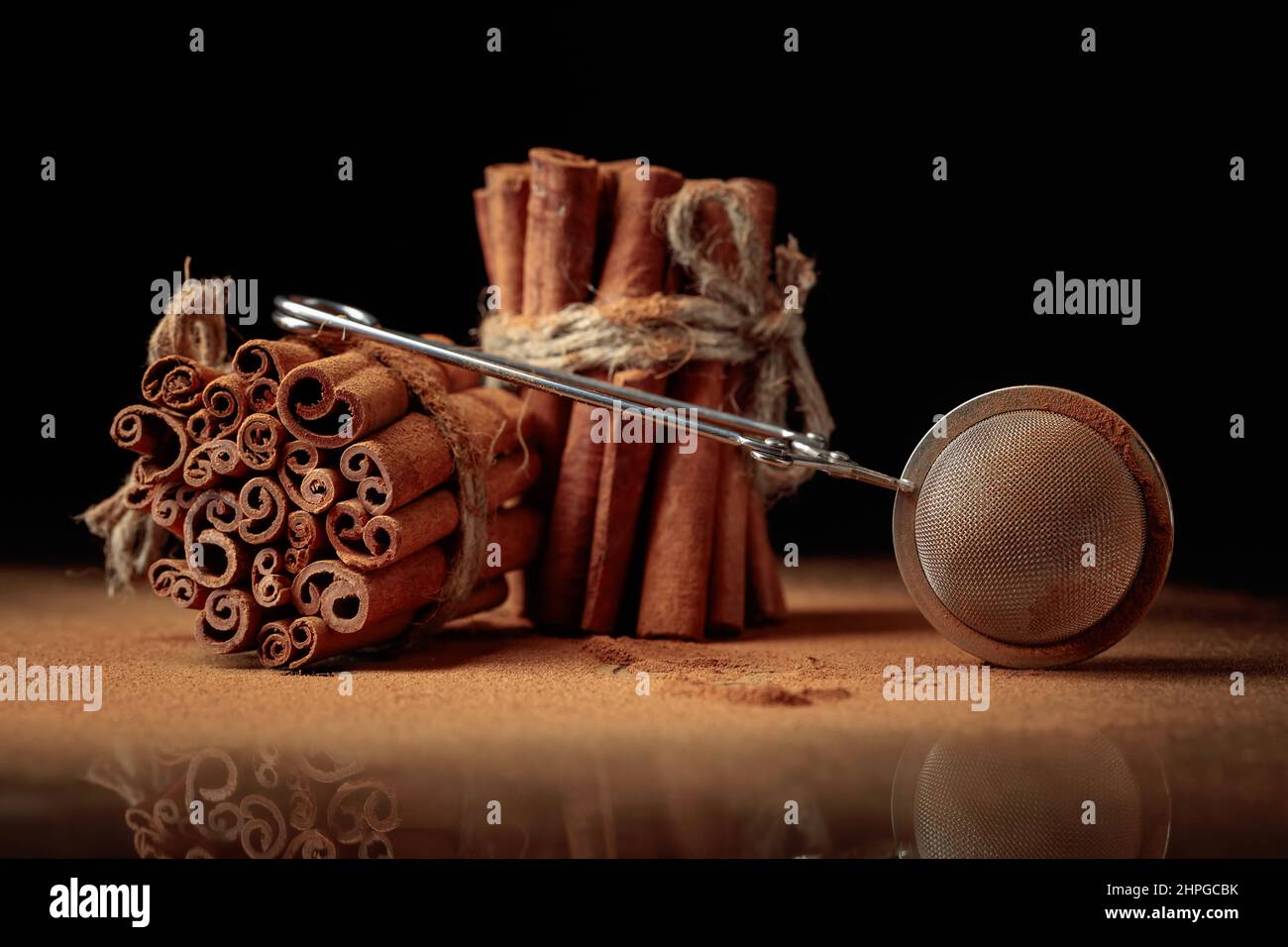 Ground cinnamon, cinnamon sticks, tied with jute rope on a black ...