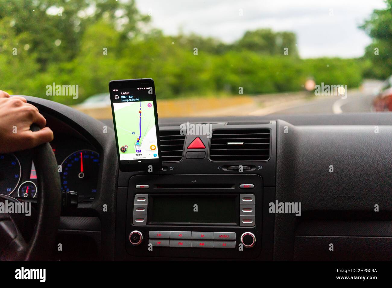 Driving and using waze maps application on smartphone on car dashboard ...
