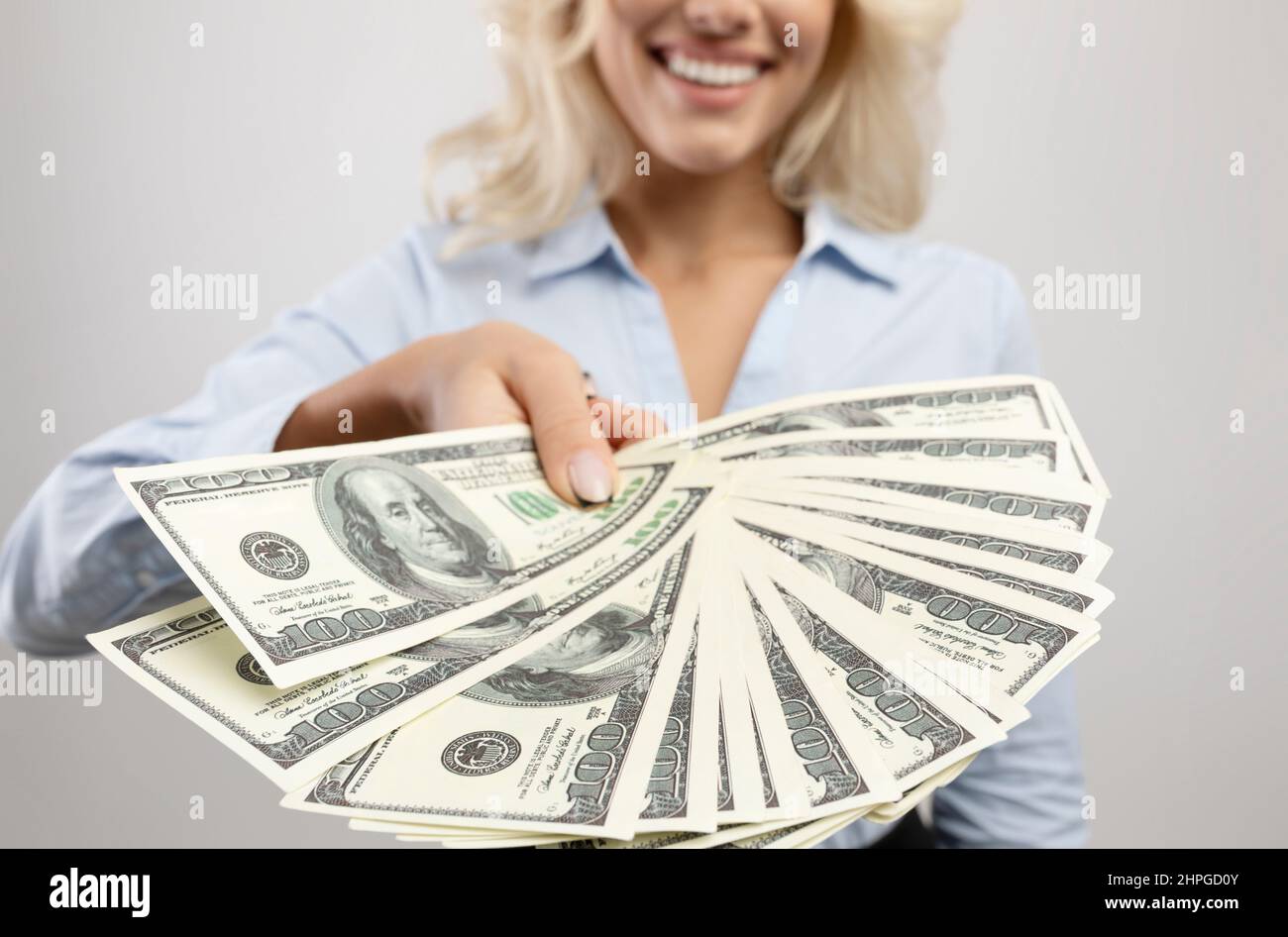 Unrecognizable businesswoman holding fan of American money over light ...
