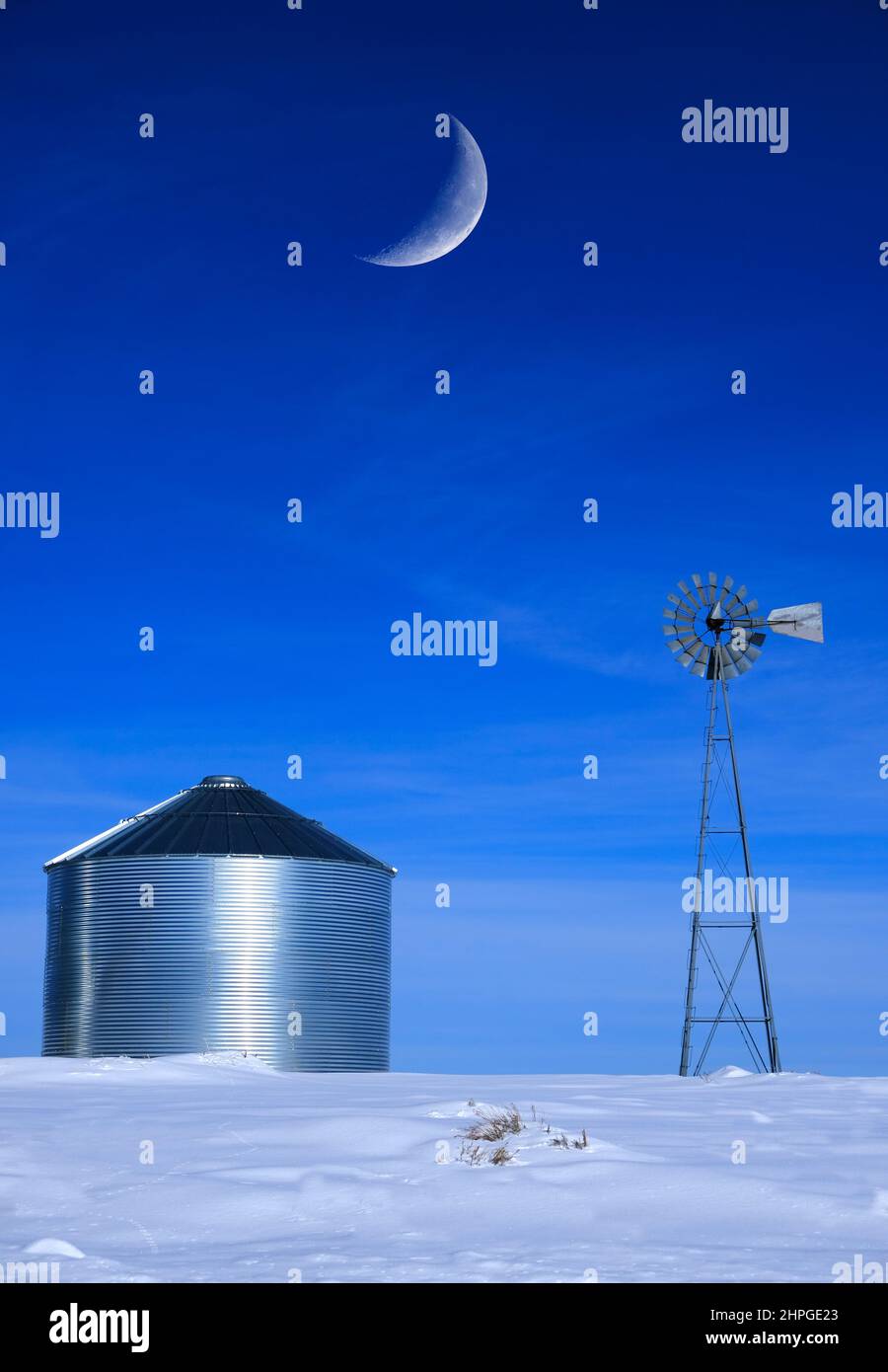 Windmill and steel grain silos in winter snow with blue sky on farm for ...