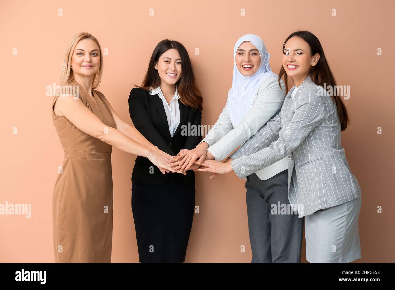 Beautiful women putting hands together on color background. Unity ...