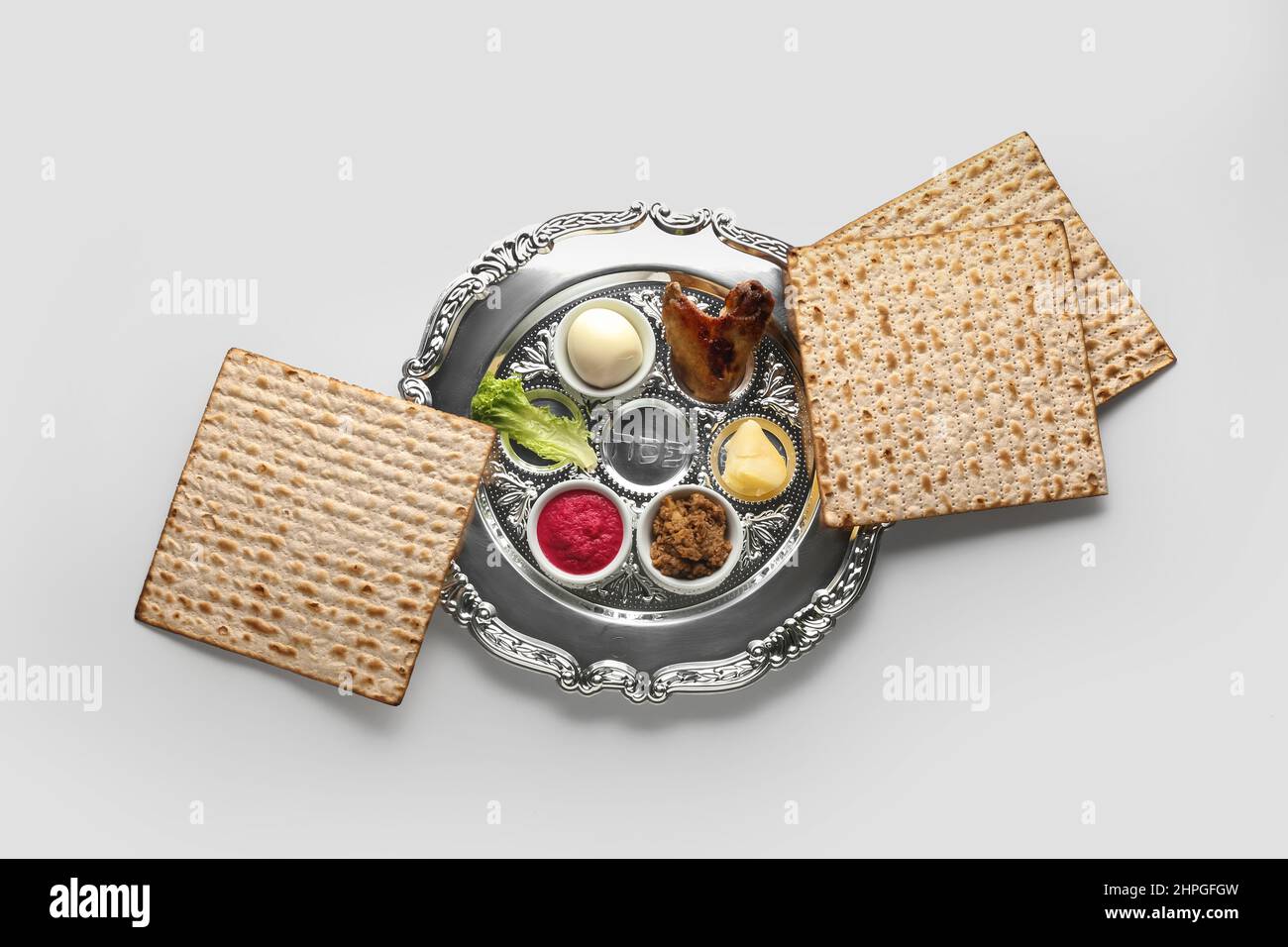 Passover Seder plate with traditional food and matza on white ...
