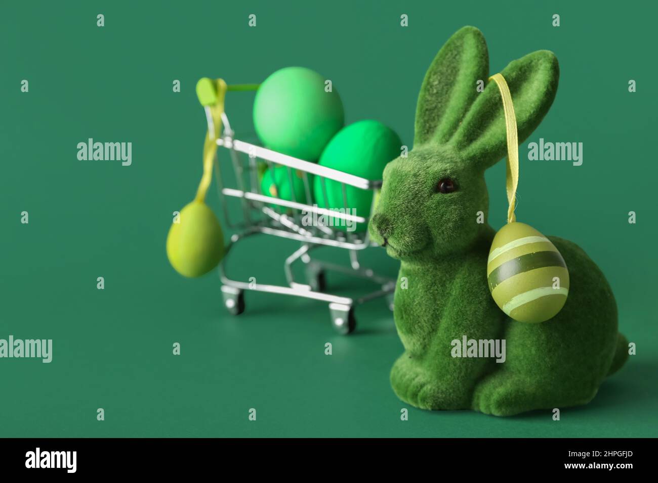 Cute Easter bunny and shopping trolley with painted eggs on green ...