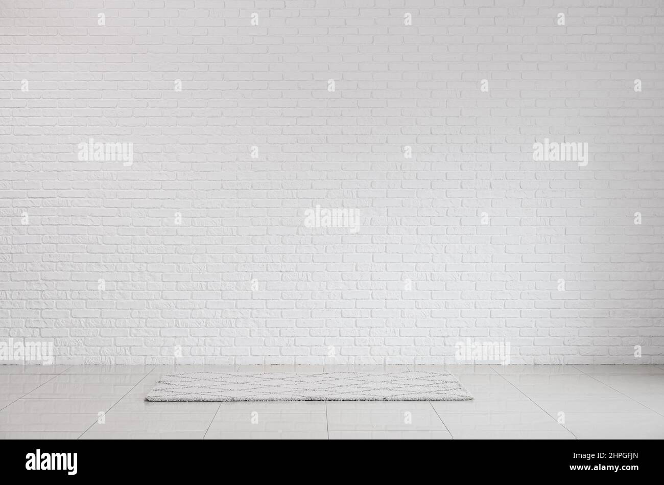 View of white brick wall and carpet in big room Stock Photo - Alamy