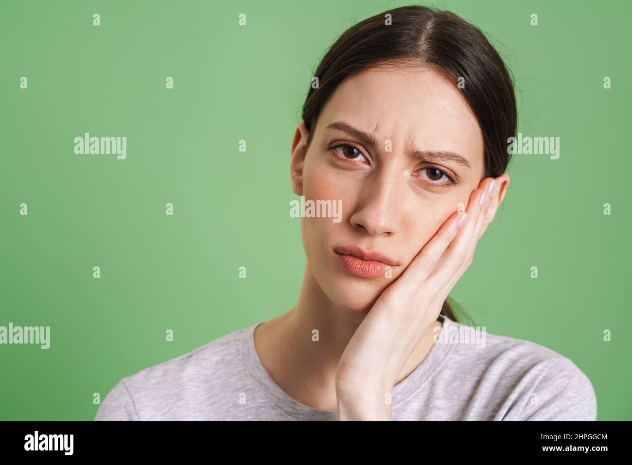 Young brunette woman frowning while touching her cheek isolated over ...