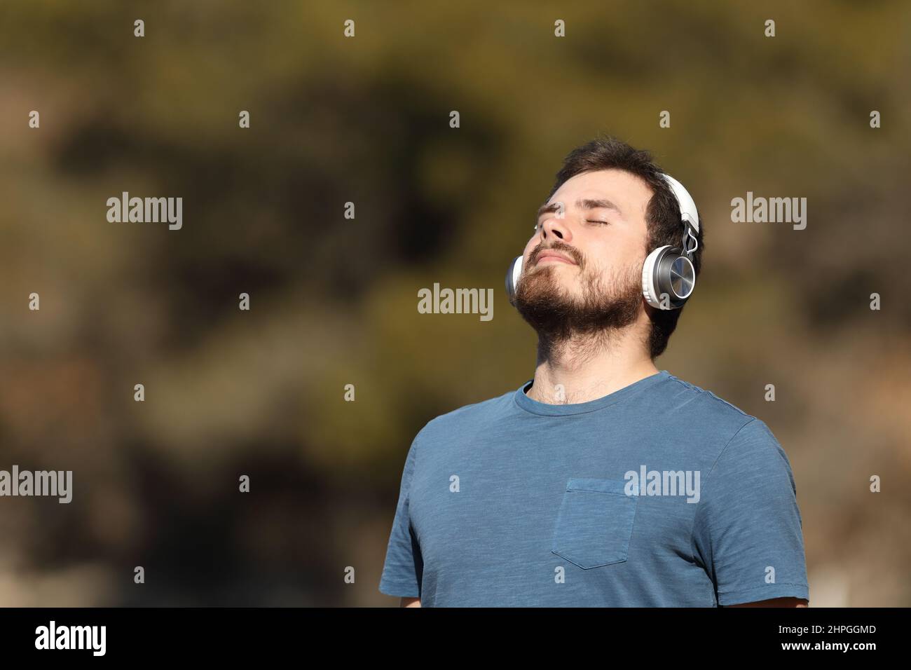 Relaxed man breathing fresh air and meditating listening audio guide ...