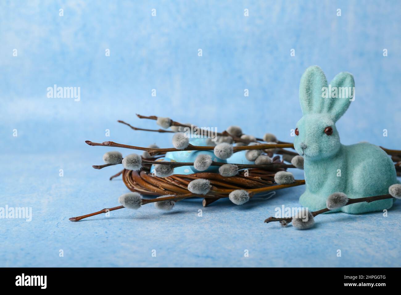Willow branches, nest with painted eggs and Easter bunny on blue ...