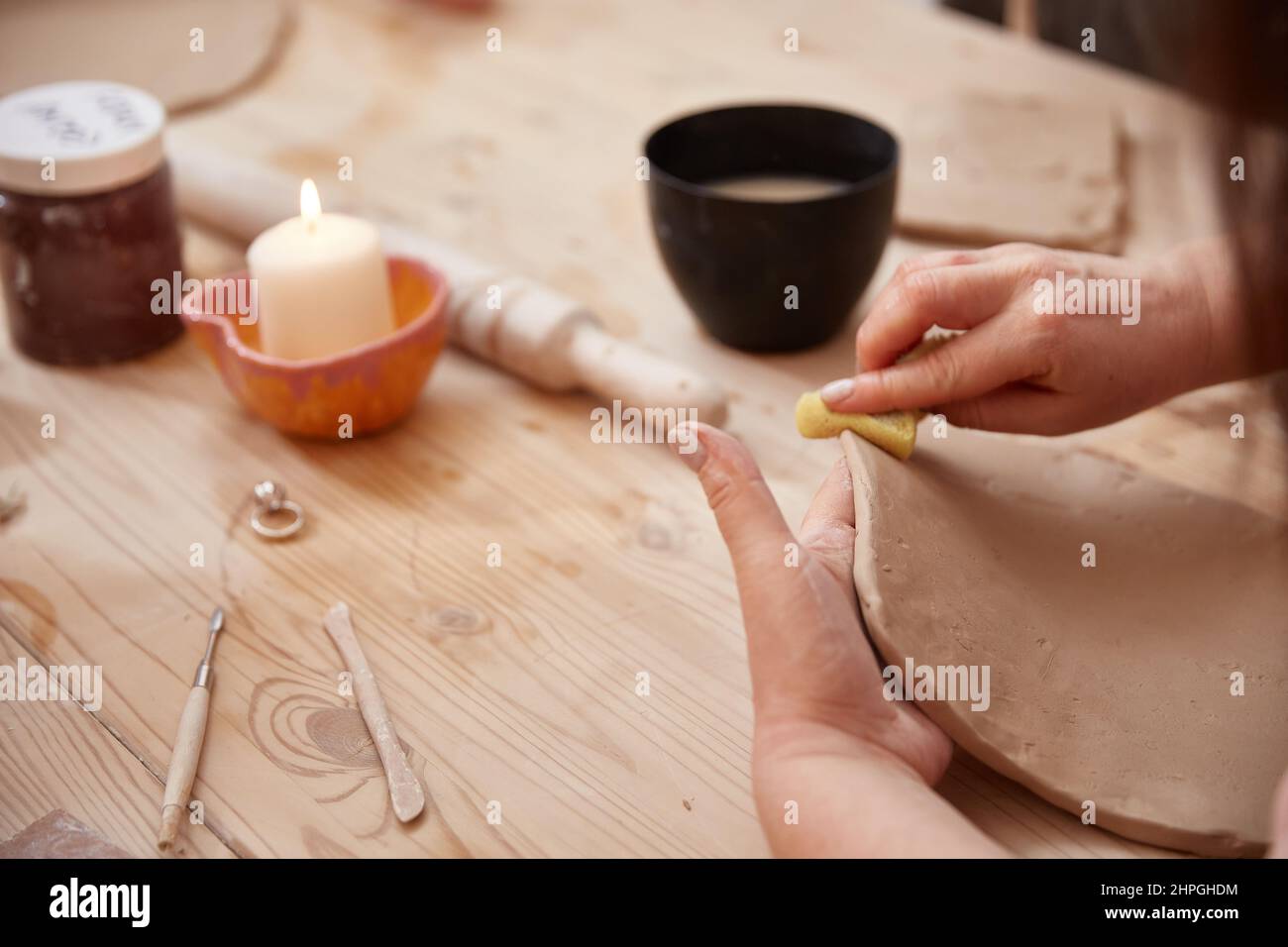 The potter's woman hands sculpt a plate or panel out of clay. The ...