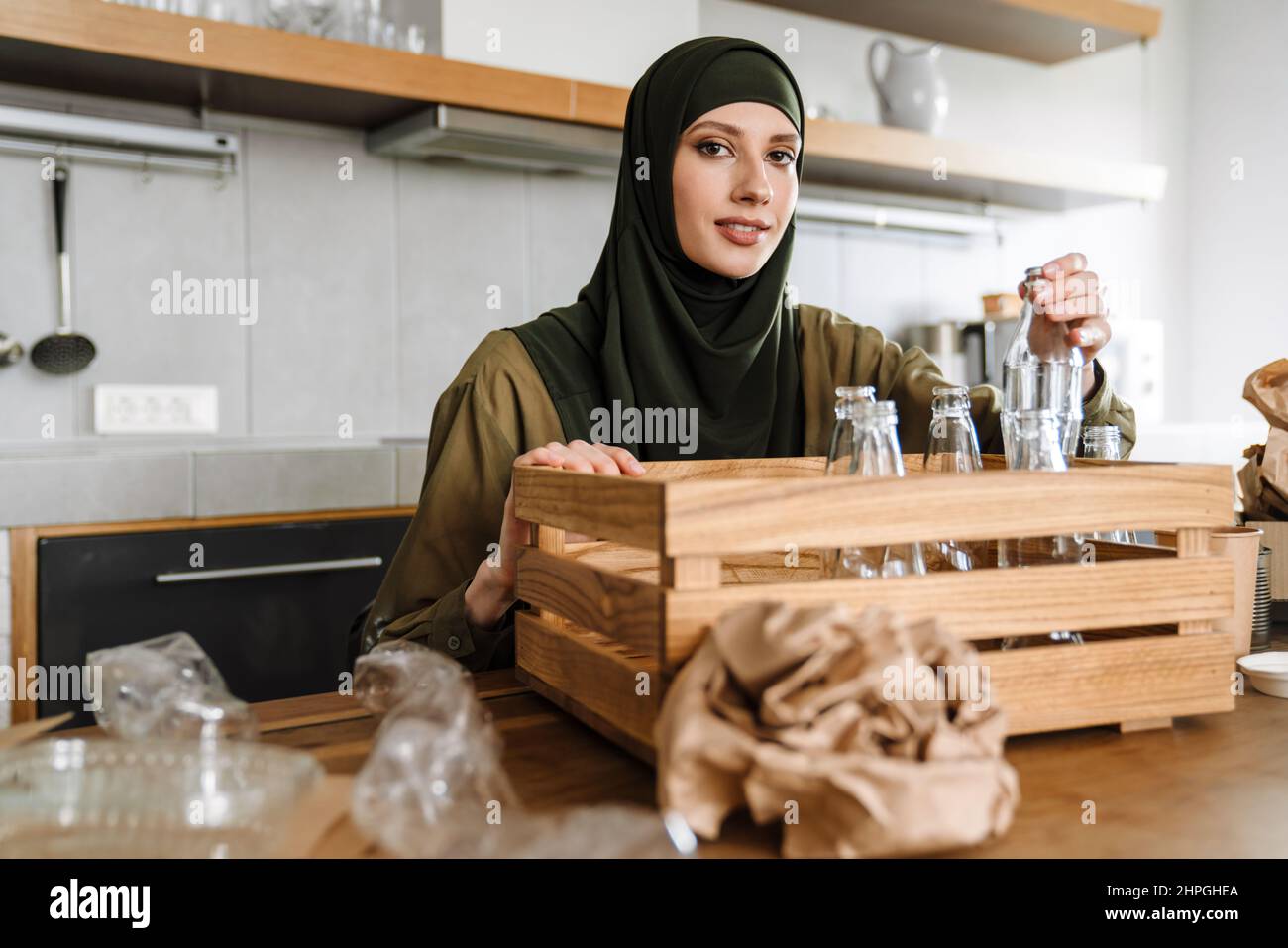 Smiling islamic woman in hijab sorting glass bottles and plastic ...