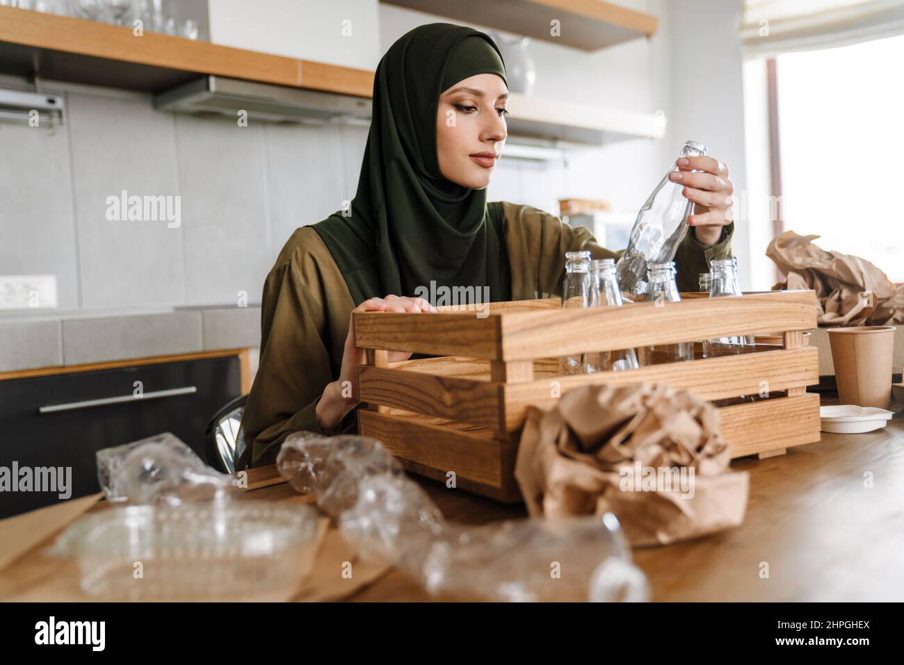 Smiling islamic woman in hijab sorting glass bottles and plastic ...