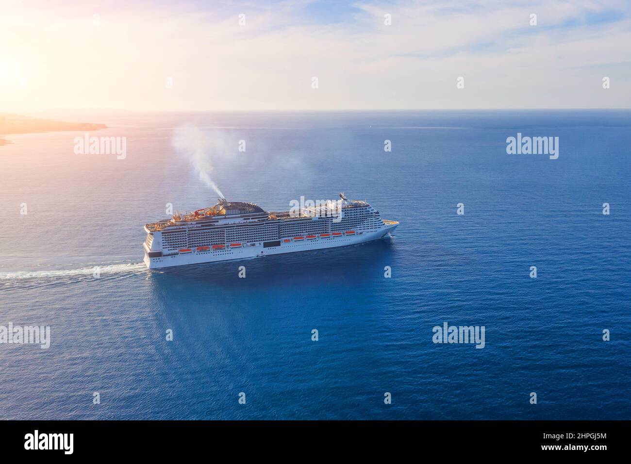 Cruise ship with smoke from the chimney goes to the open sea at sunset ...