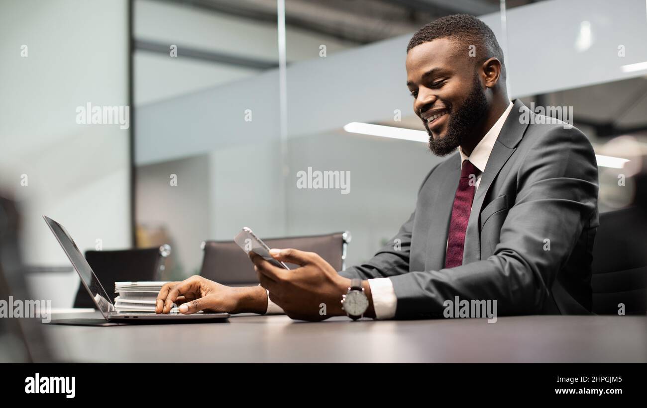 Handsome young black businessman in nice suit sitting at workdesk at ...