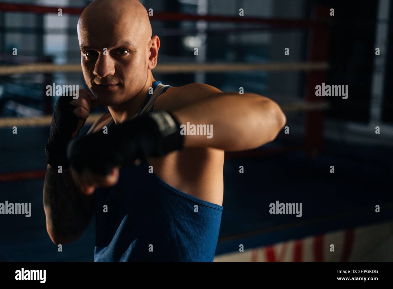 Front view of serious aggressive boxer male wearing bandages punching ...