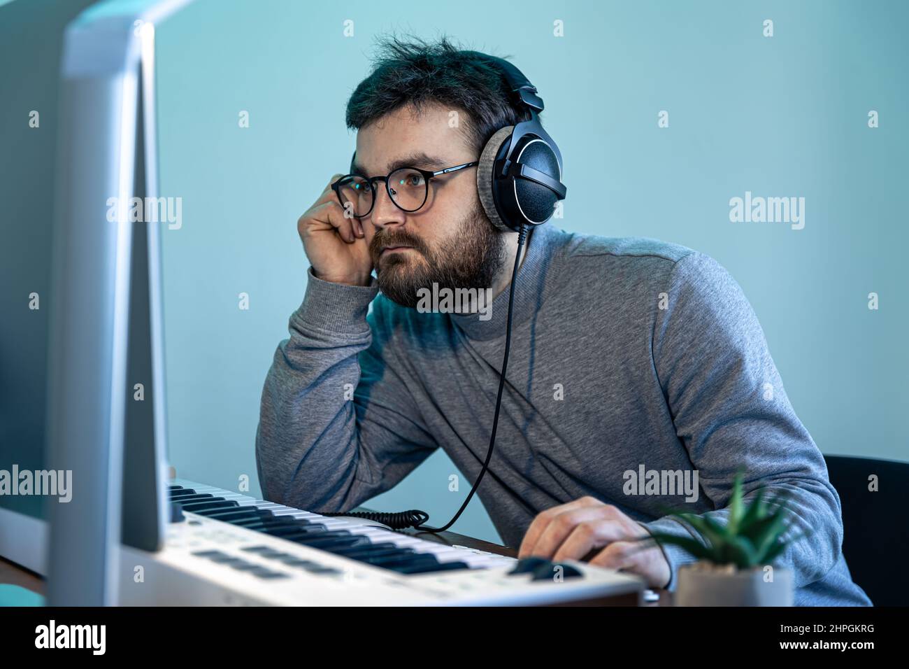 Male musician creates music using computer and keyboard, musician ...
