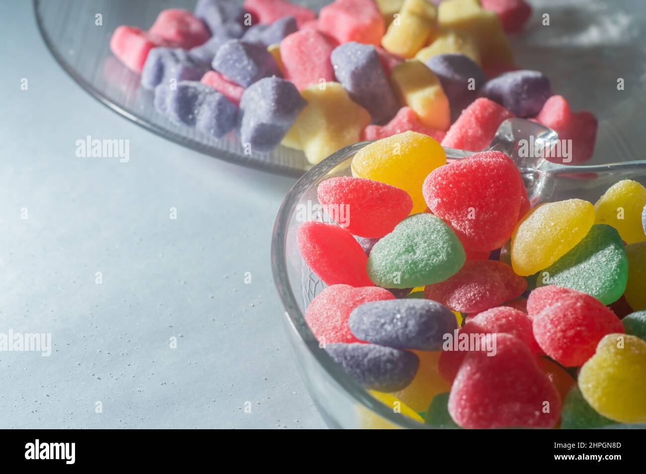 Assorted colorful sweets in a trasparente bowl, light blue background ...