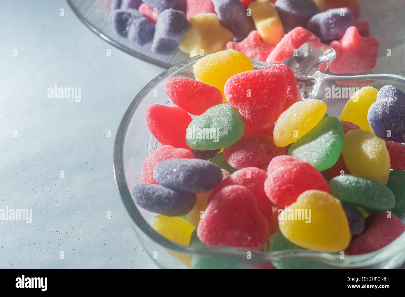 Assorted colorful sweets in a trasparente bowl, light blue background ...