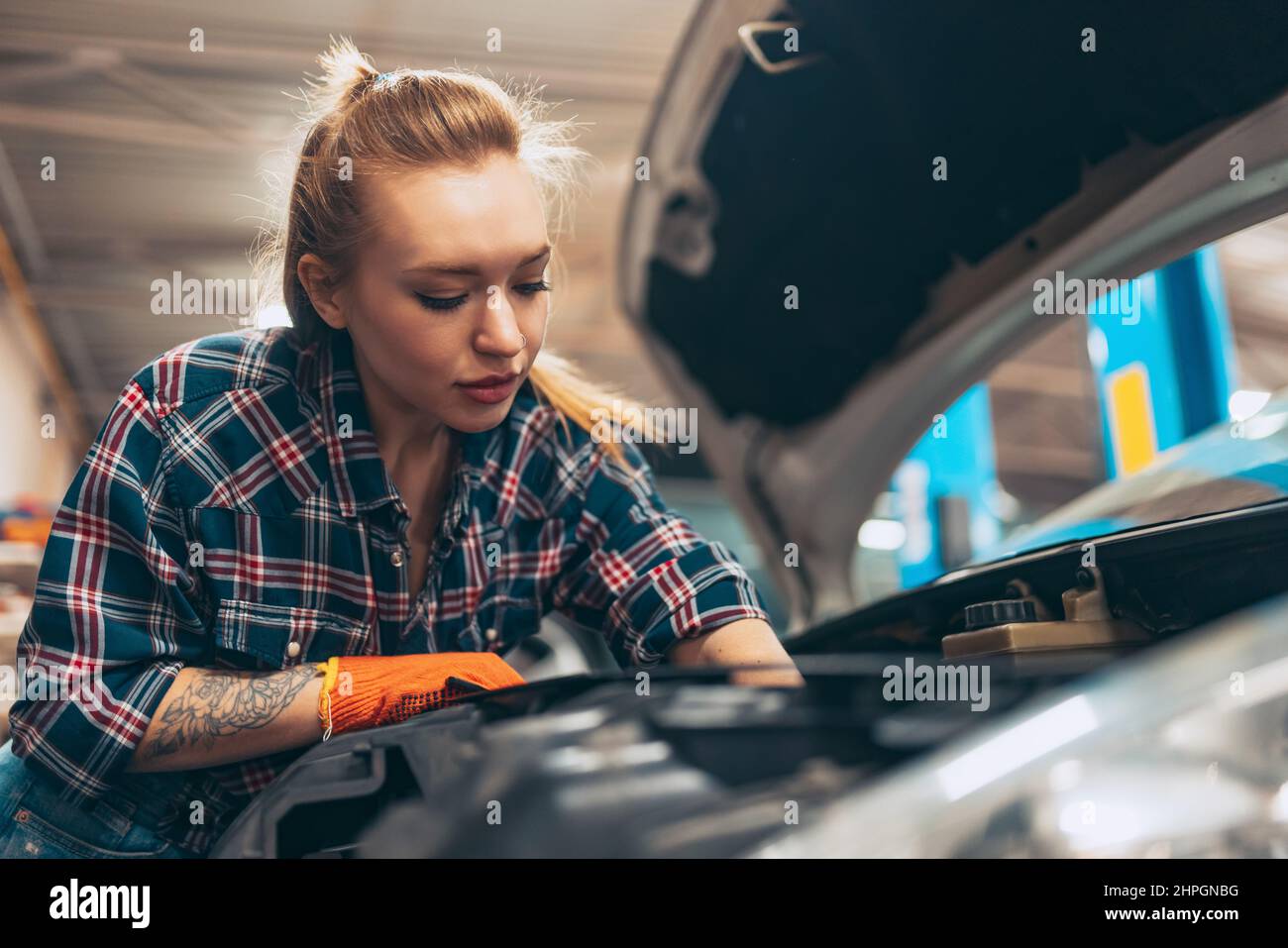 Car reapir. Young red-headed girl, auto mechanic working at auto ...