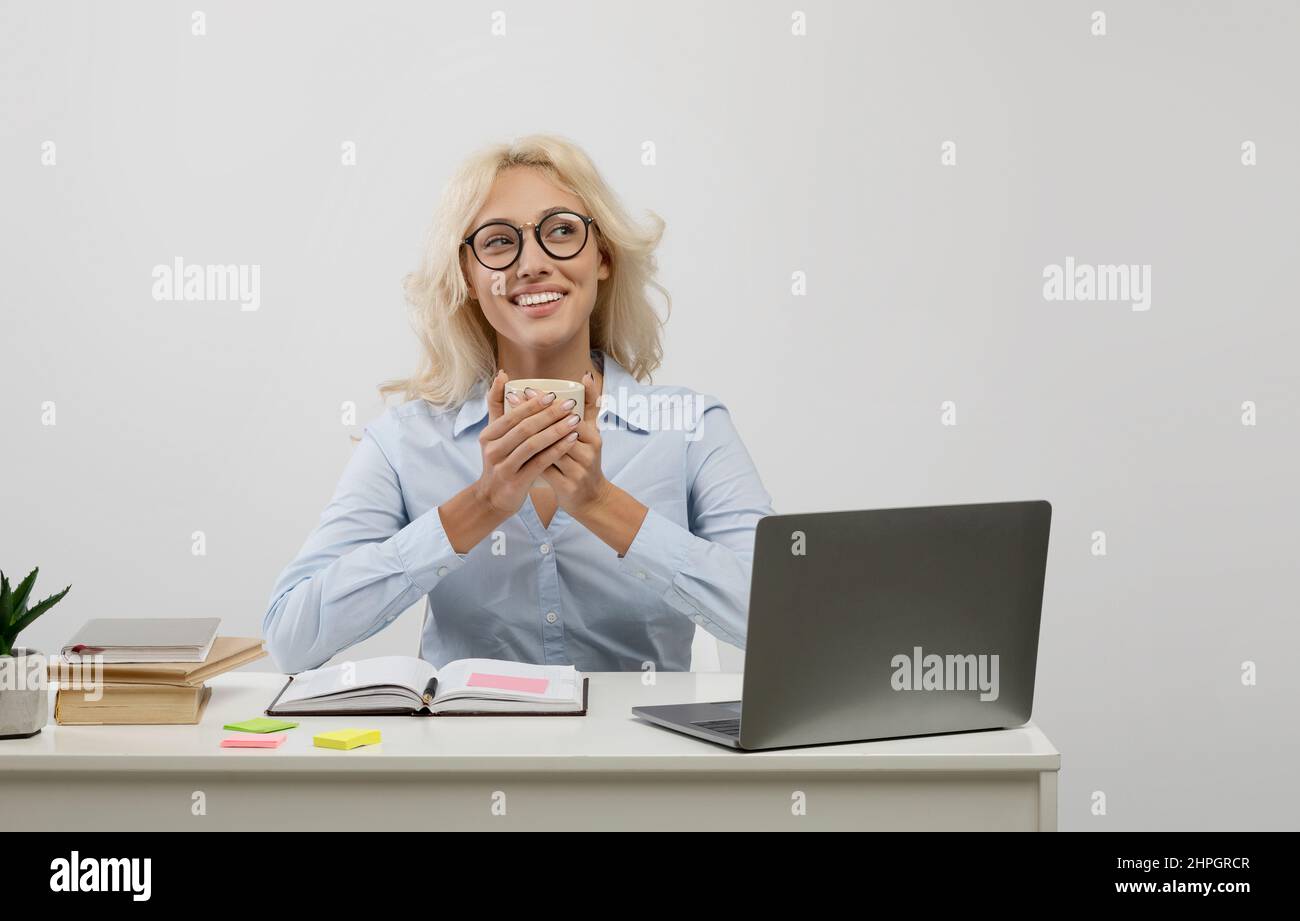 Cup of tea and chill. Happy young office worker drinking hot beverage ...