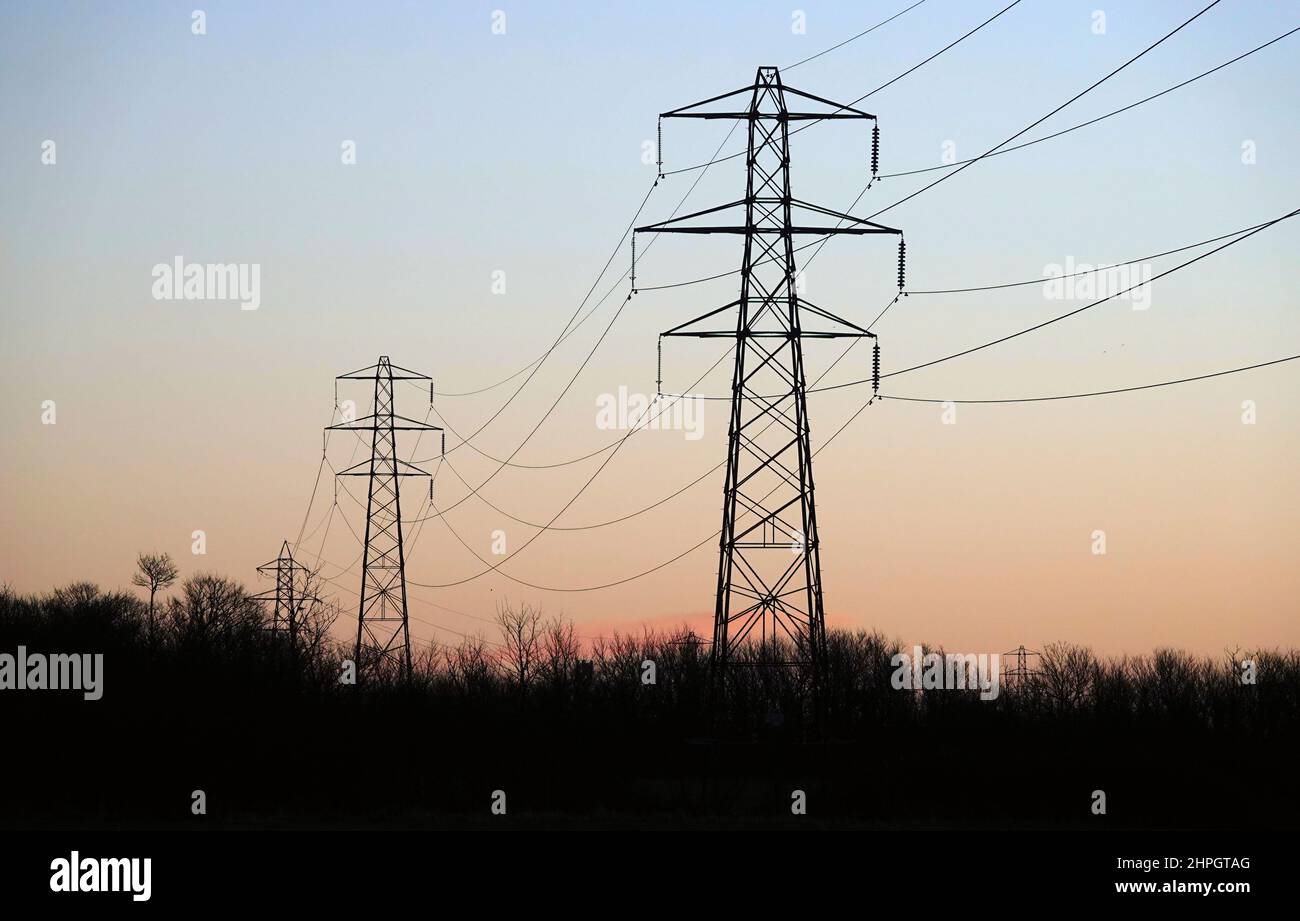 A striking sunrise shot of electricity pylons supporting overhead power ...