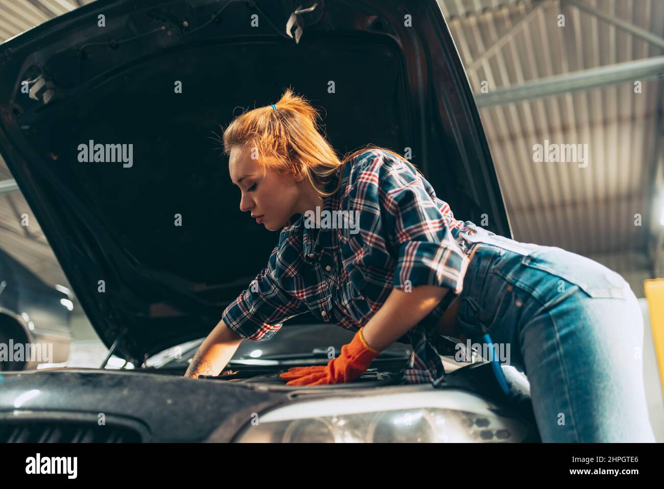 Car reapir. Young red-headed girl, auto mechanic working at auto ...