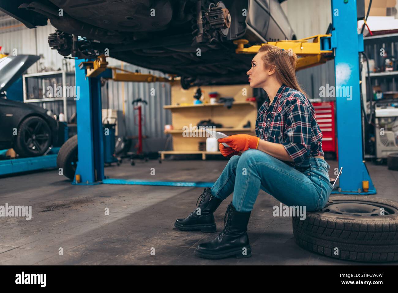Portrait of beautiful young red-headed girl, auto mechanic at auto ...