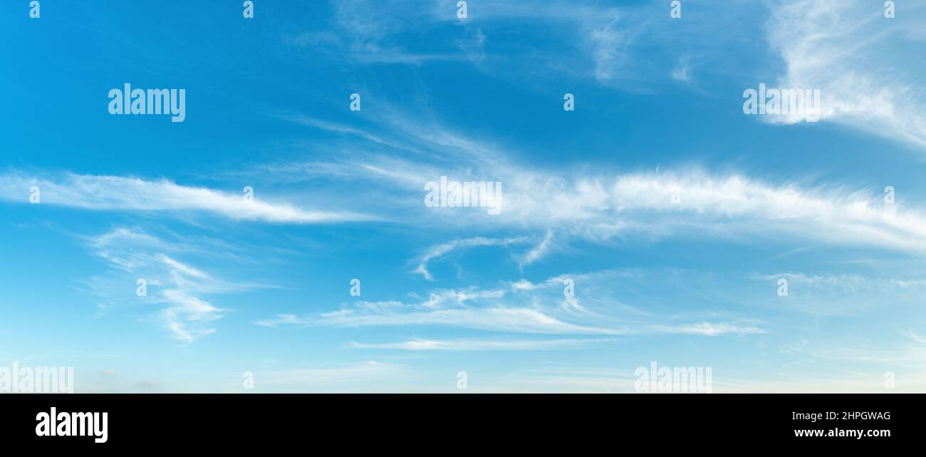 Sparse translucent cirrus clouds high in the clear blue sky. Wide ...