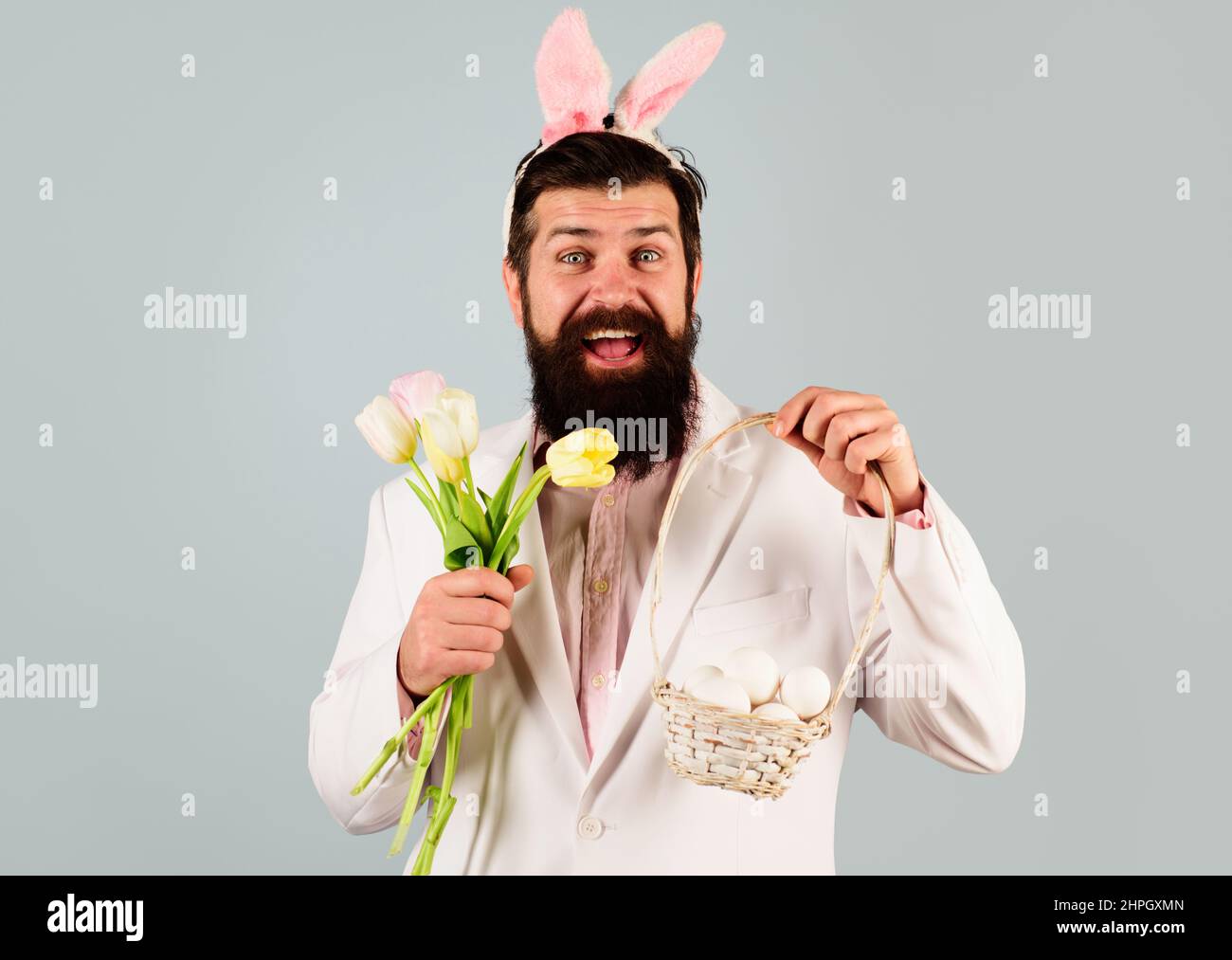 Happy Easter. Rabbit man in bunny ears with flower and basket eggs ...