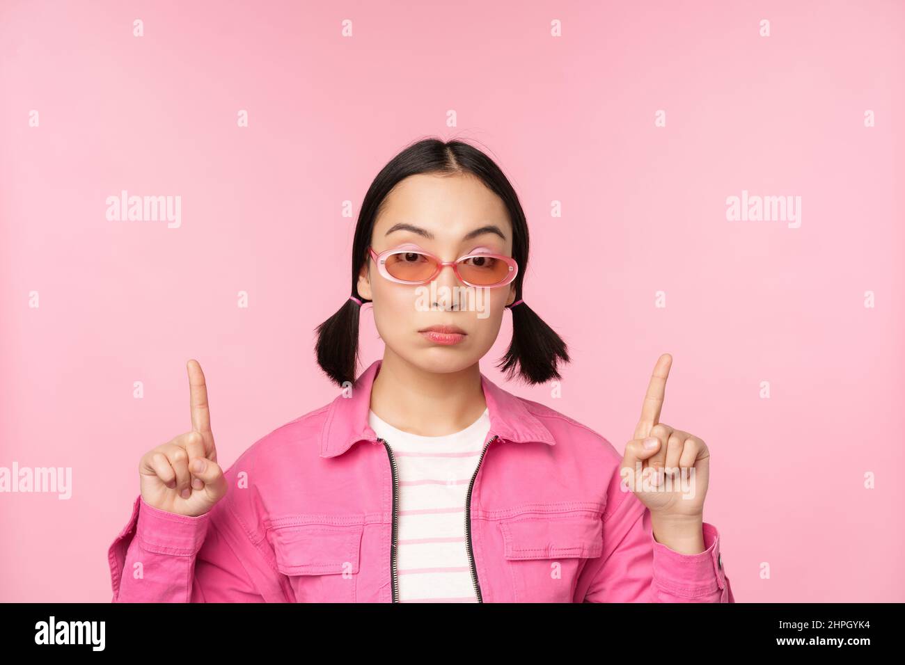 Close up portrait of asian stylish girl, looking skeptical, pointing ...