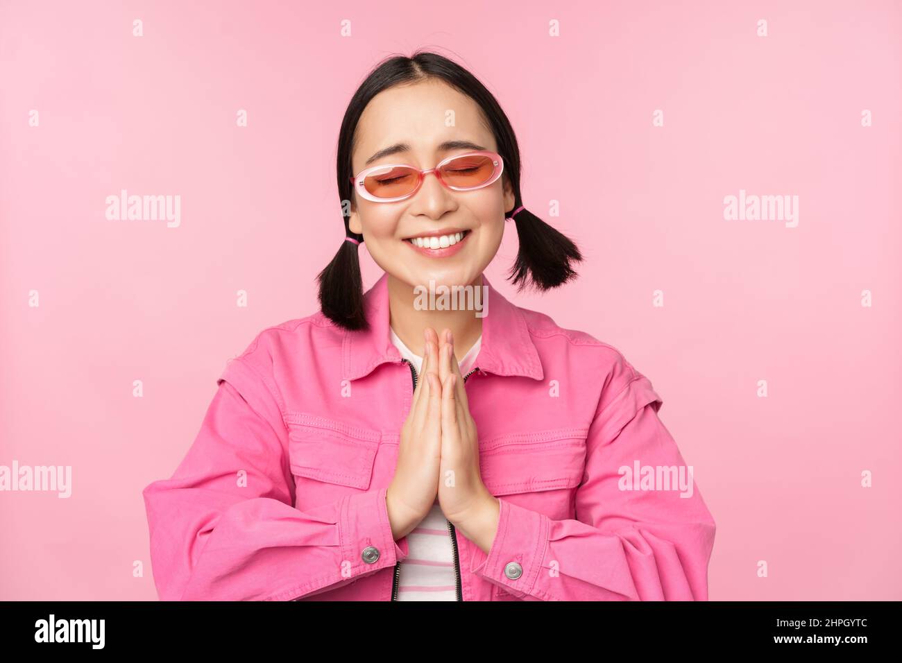 Please. Cute asian girl asking favour, begging, standing against studio ...