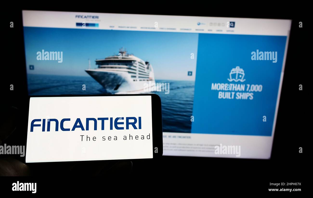 Person holding smartphone with logo of Italian shipbuilding company ...