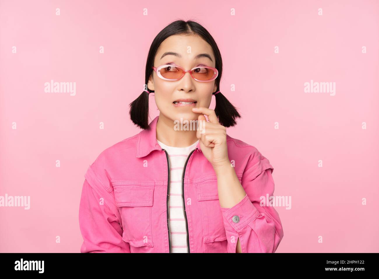 Stylish asian girl in sunglasses, looks thoughtful or intrigued, wants ...