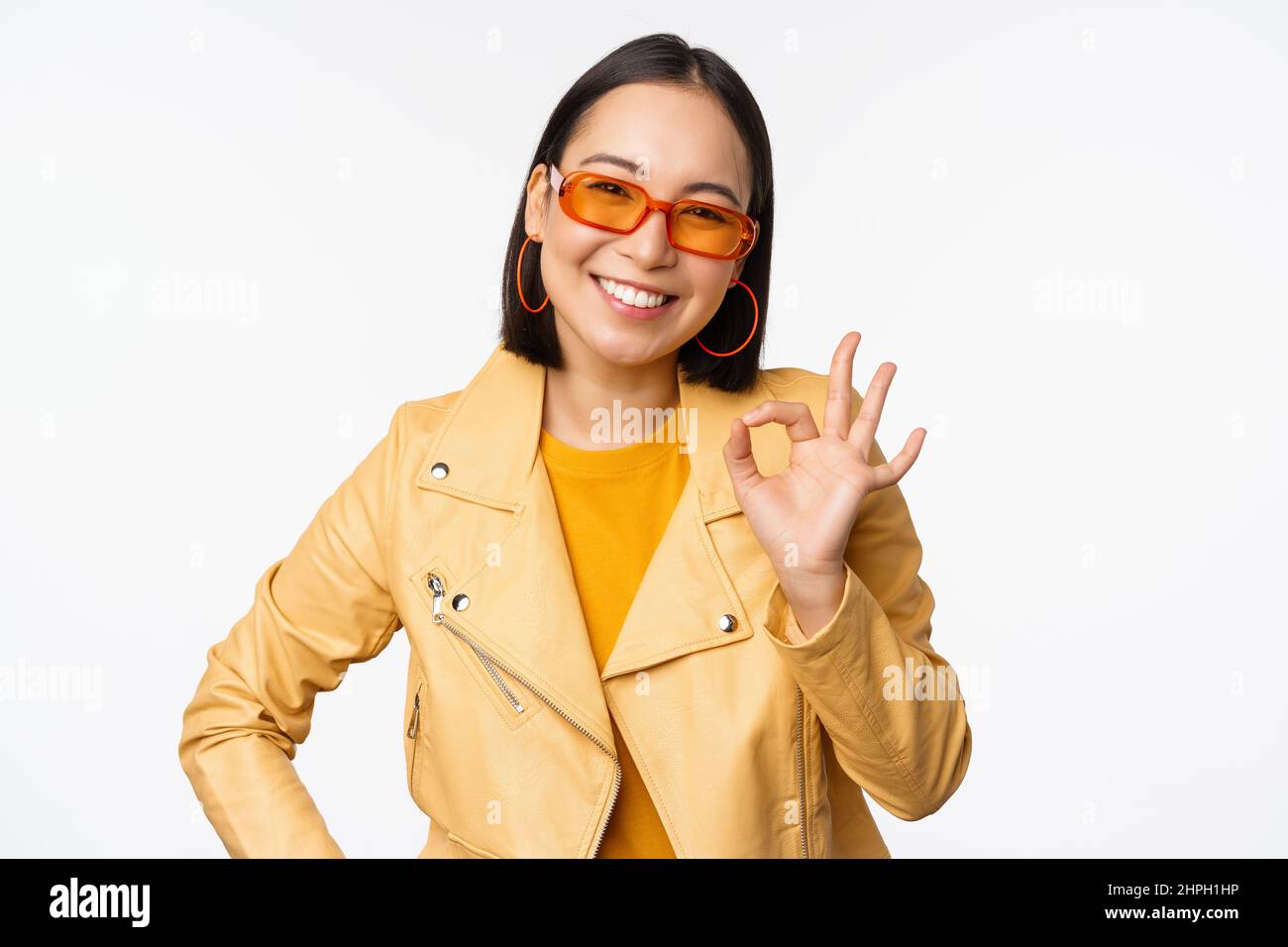 Excellent. Smiling asian girl shows okay, ok sign, nod in approval ...