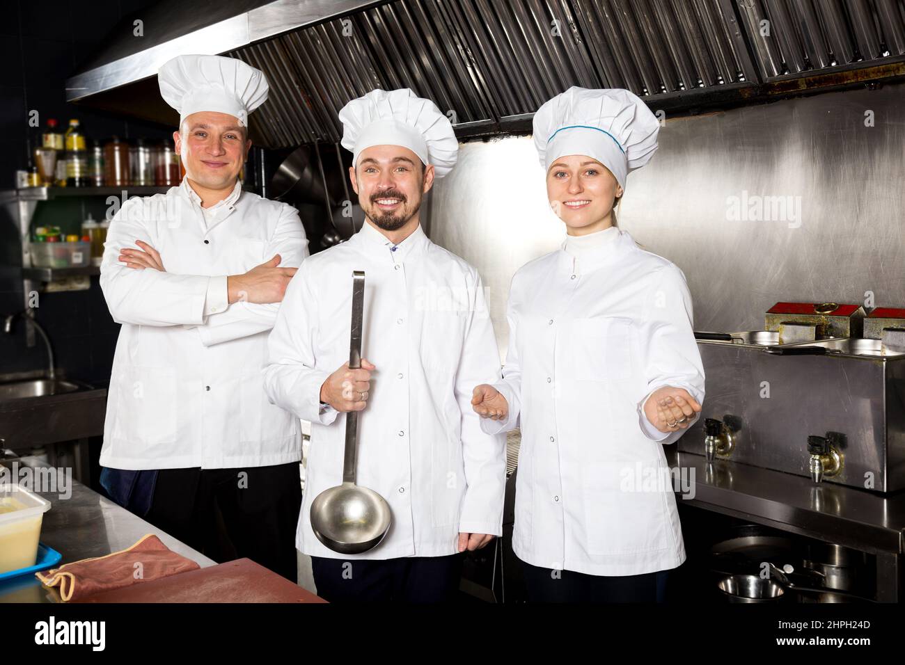 Cheerful professional chefs showing their workplace in restaurant’s ...
