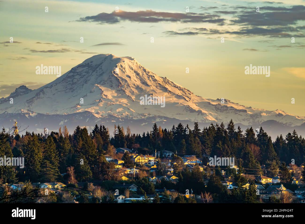 A view of clouds over Mount Rainier with trees in the foreground Stock ...