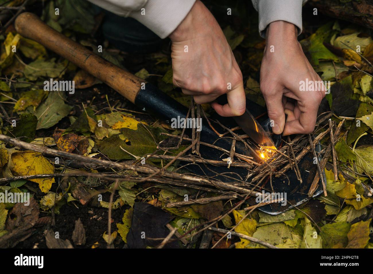 Close-up cropped shot of scout male lighting fire, starting campfire ...