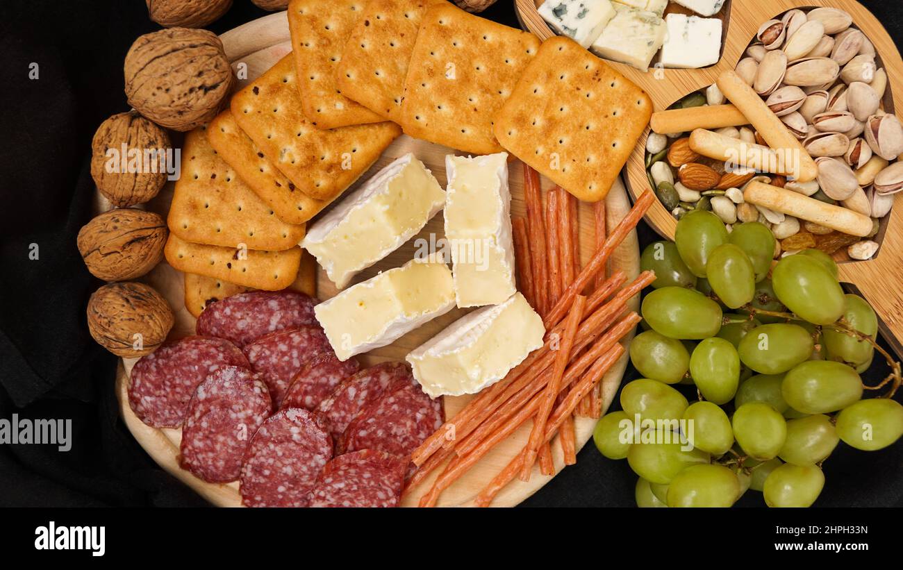 Cheese platter with assorted cheeses, grapes, nuts over black ...