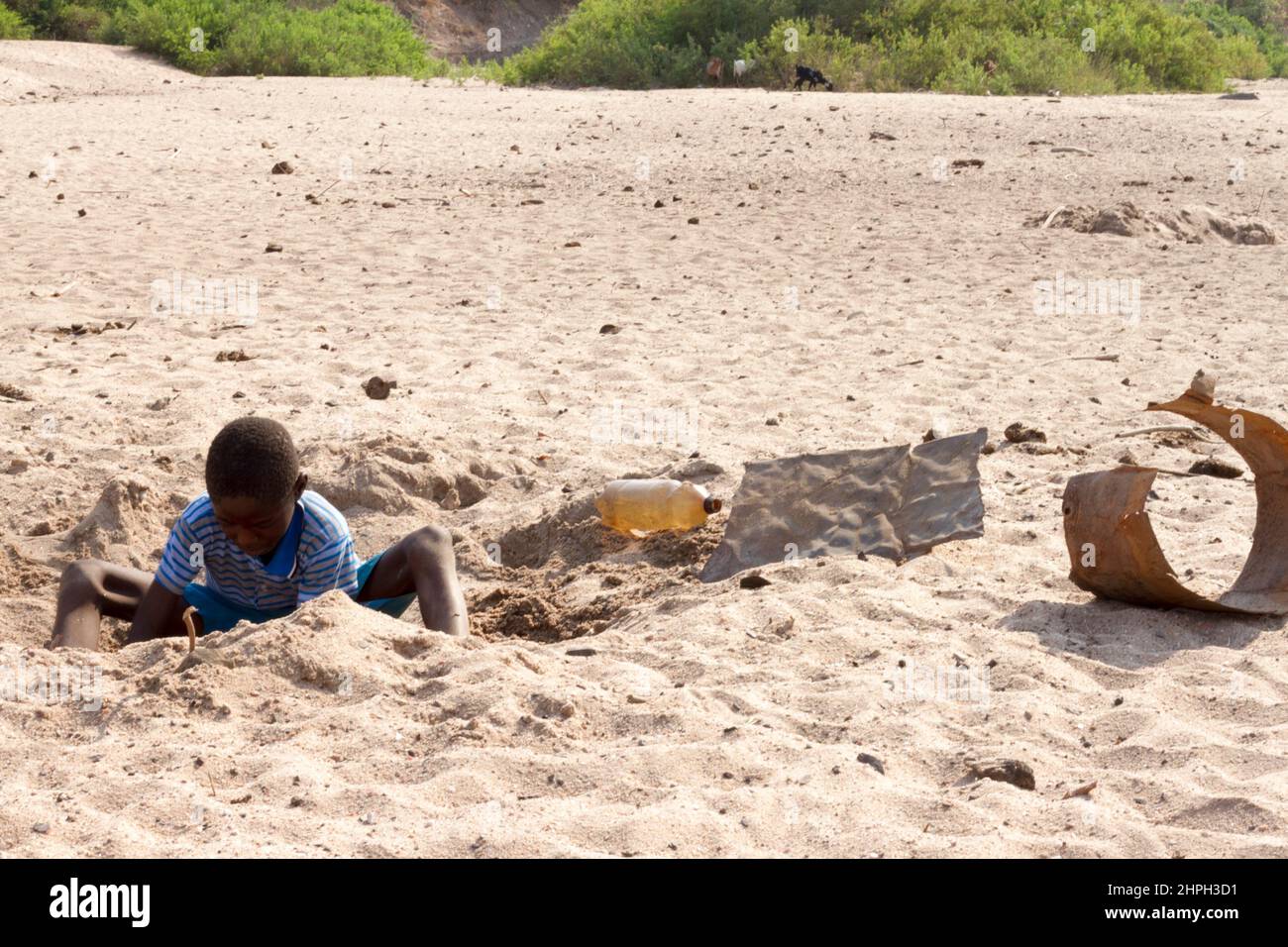 A young boy is seen digging in the sand of a dried up river for some ...