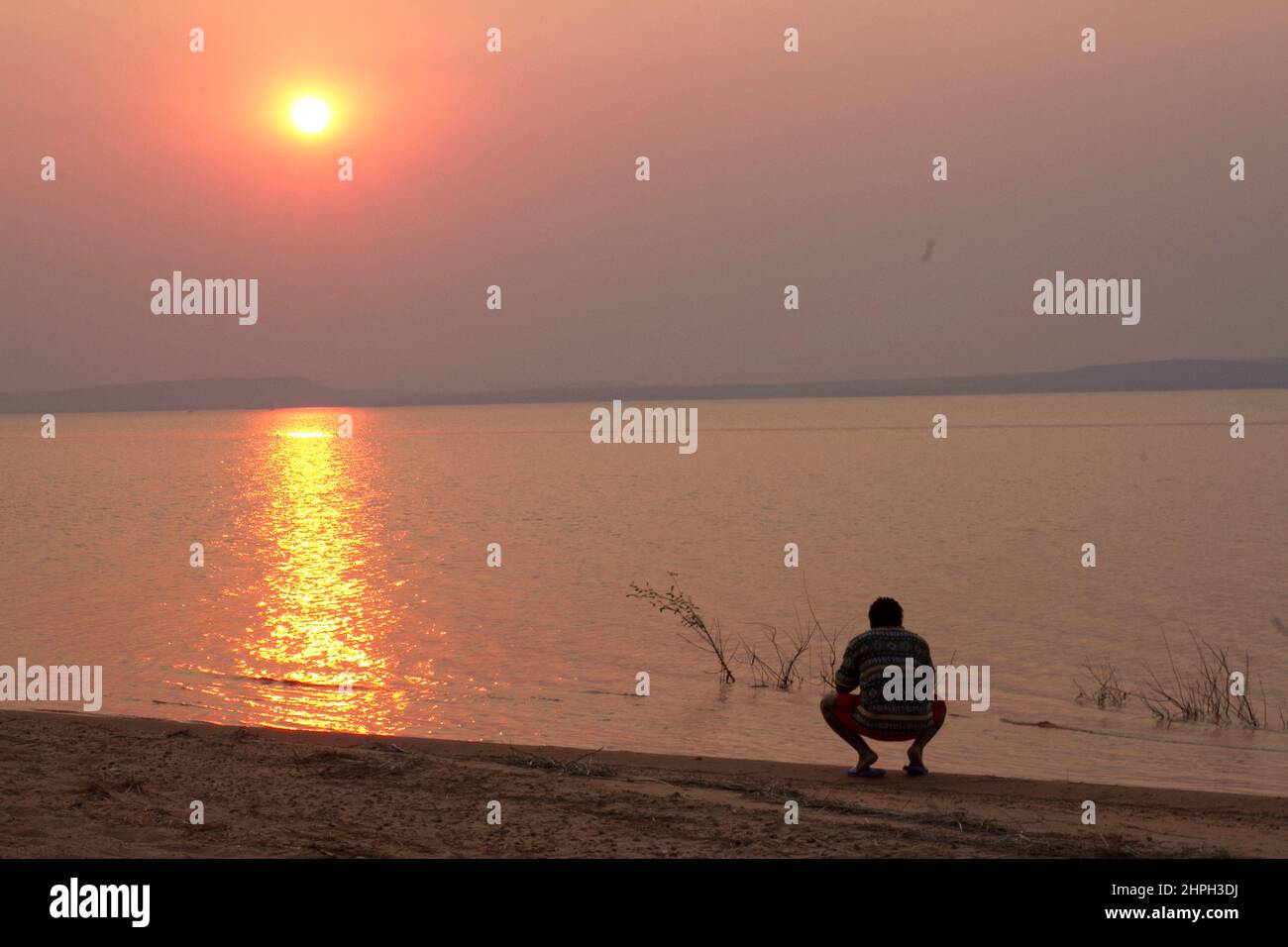 A man is seen sitting on the Zambezi river beach in Binga. Binga is in ...