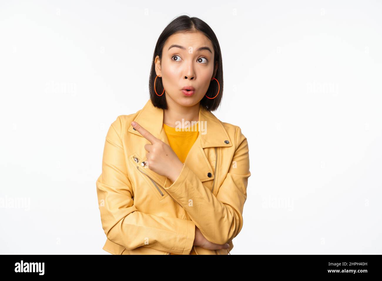 Image of surprised aisan woman pointing finger left, looking at logo or ...