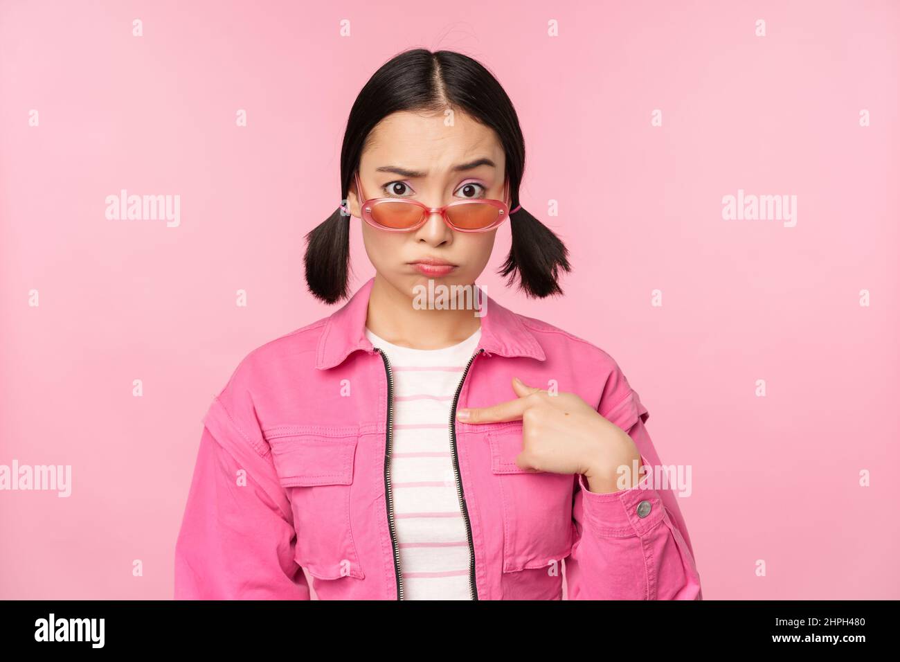 Portrait of asian girl looks confused and points at herself, perplexed ...